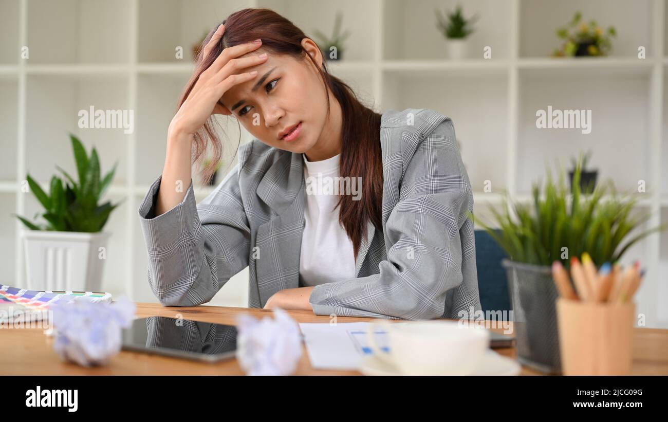 Stressed young asian female graphic designer pensive thinking about her ...