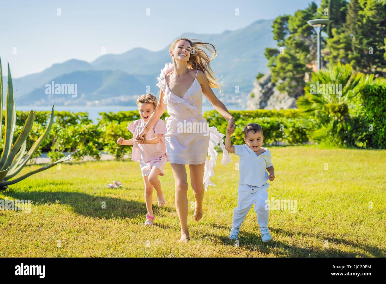 Joyful young mother playing catch together with two little children ...