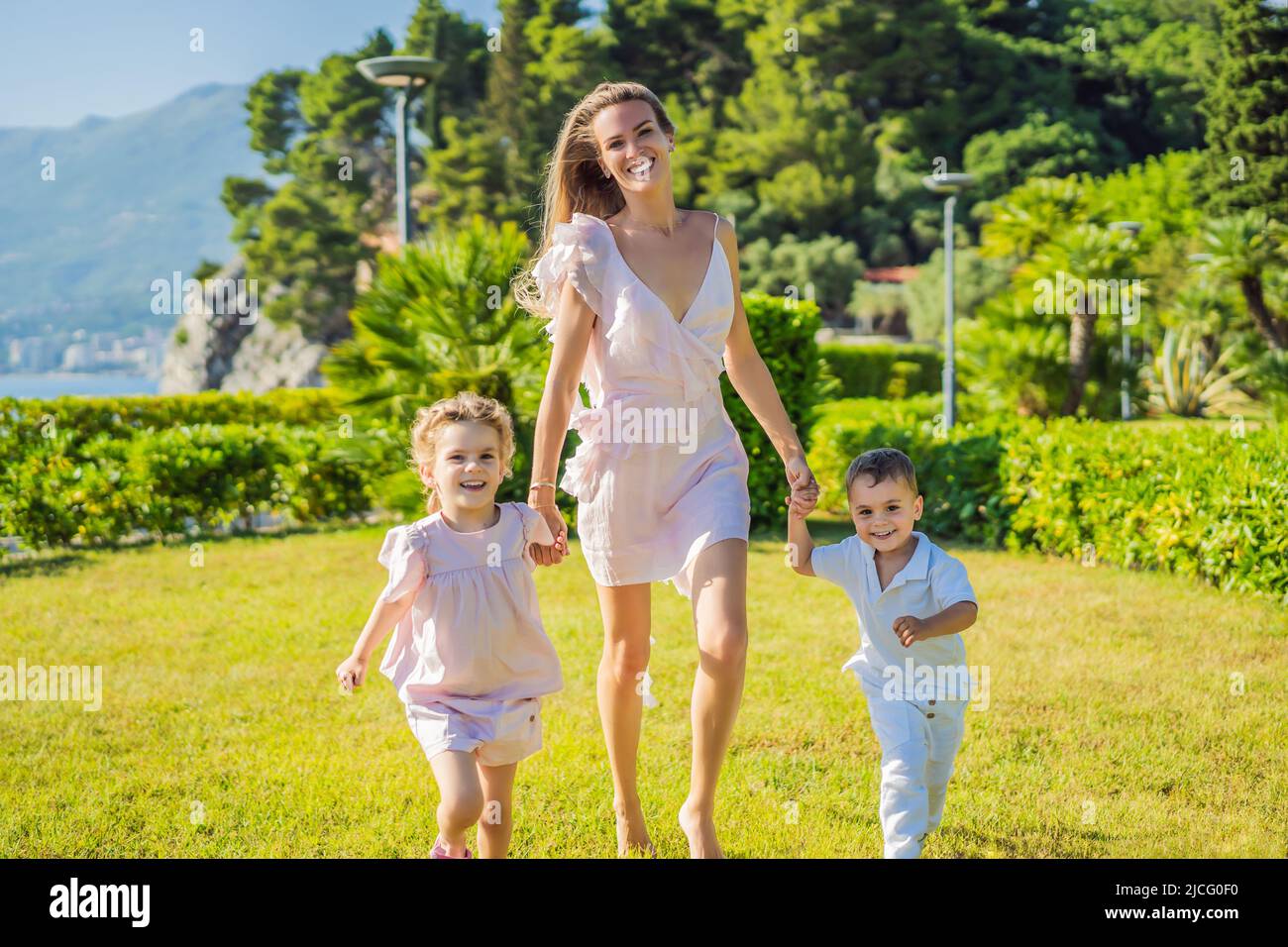 Joyful young mother playing catch together with two little children ...