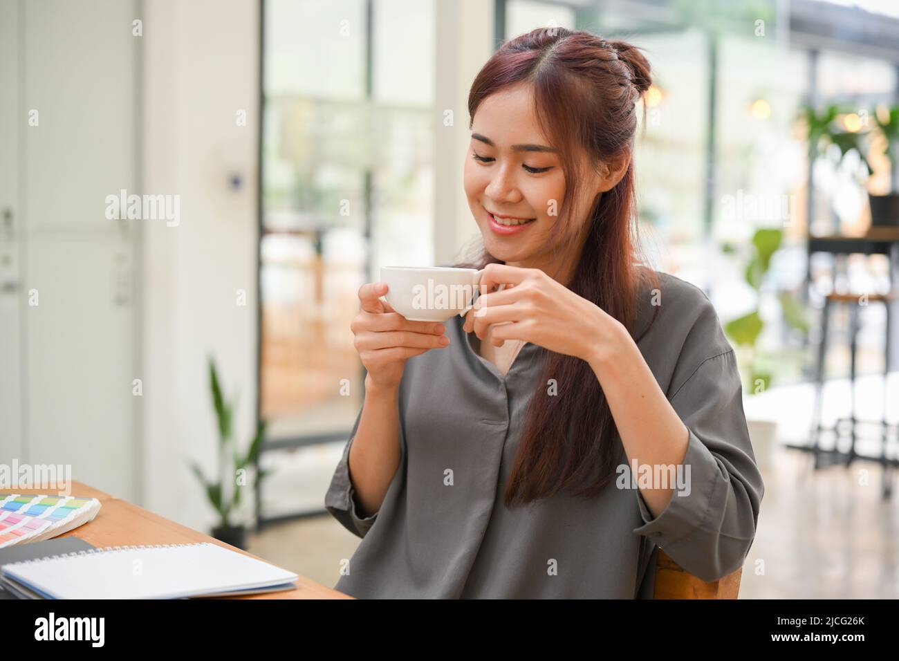 Relaxed young asian woman in casual wear enjoy sipping morning coffee ...