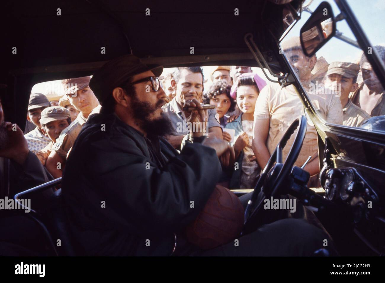 Fidel Castro is sitting at the wheel of a jeep, his compatriots are ...