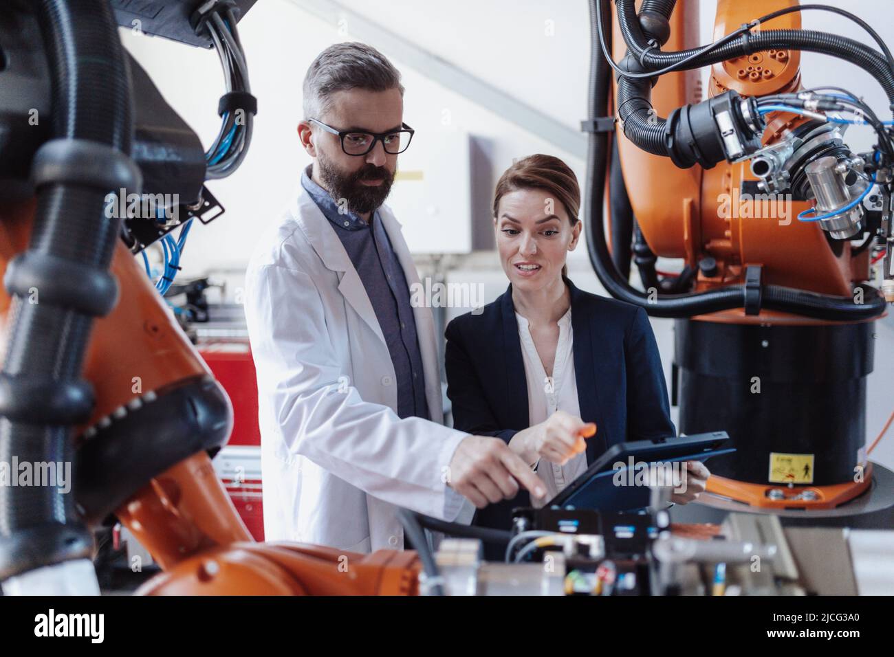 Robotics engineers with tablet dicussing and desinging modern robotic ...