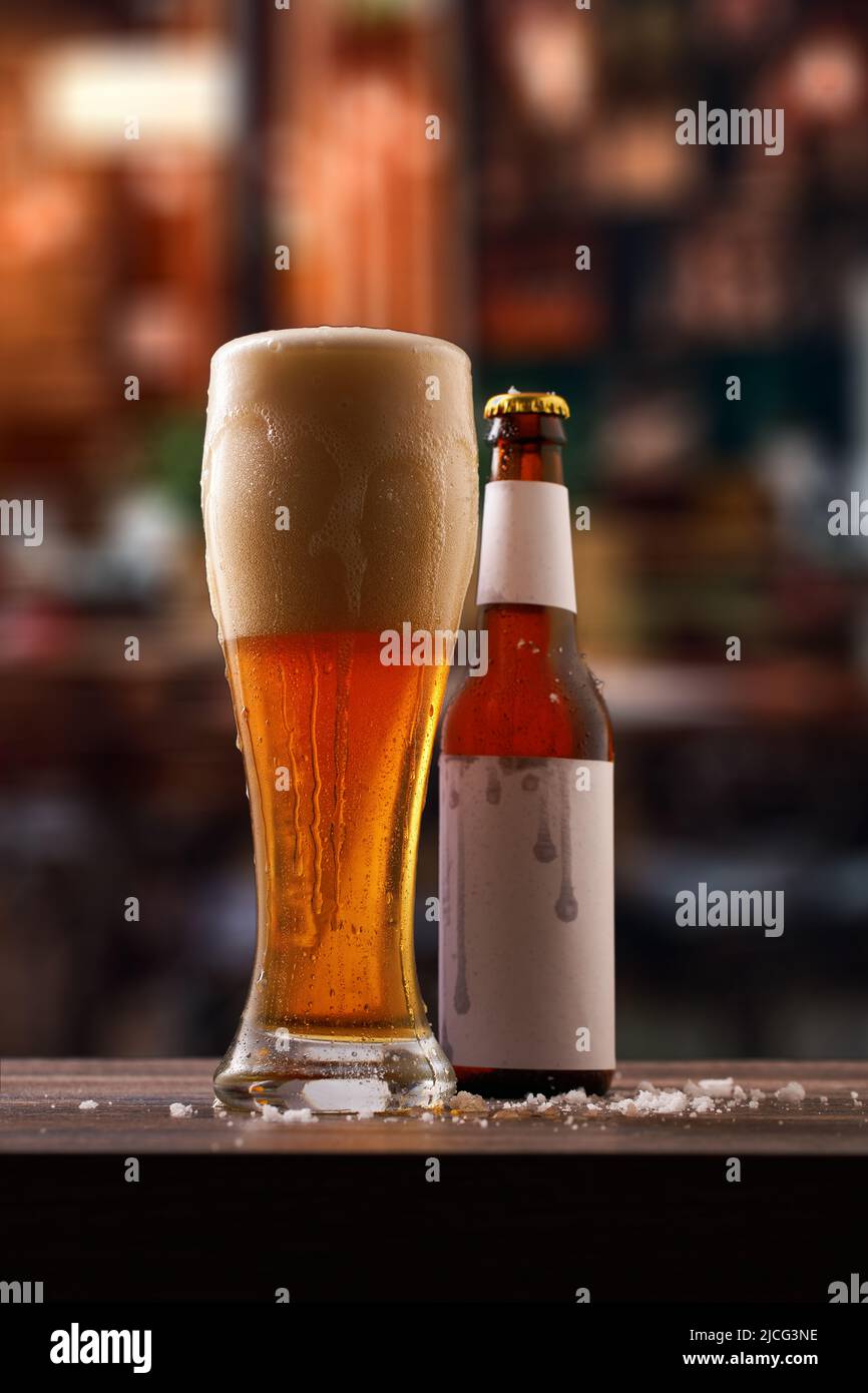 Bottle and glass of beer on counter in pub. Alcoholic beverage over pub ...