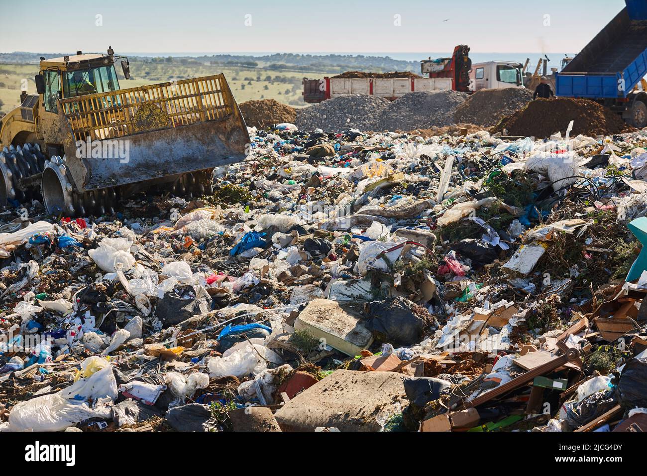 Heavy machinery shredding garbage in an open air landfill. Waste Stock ...