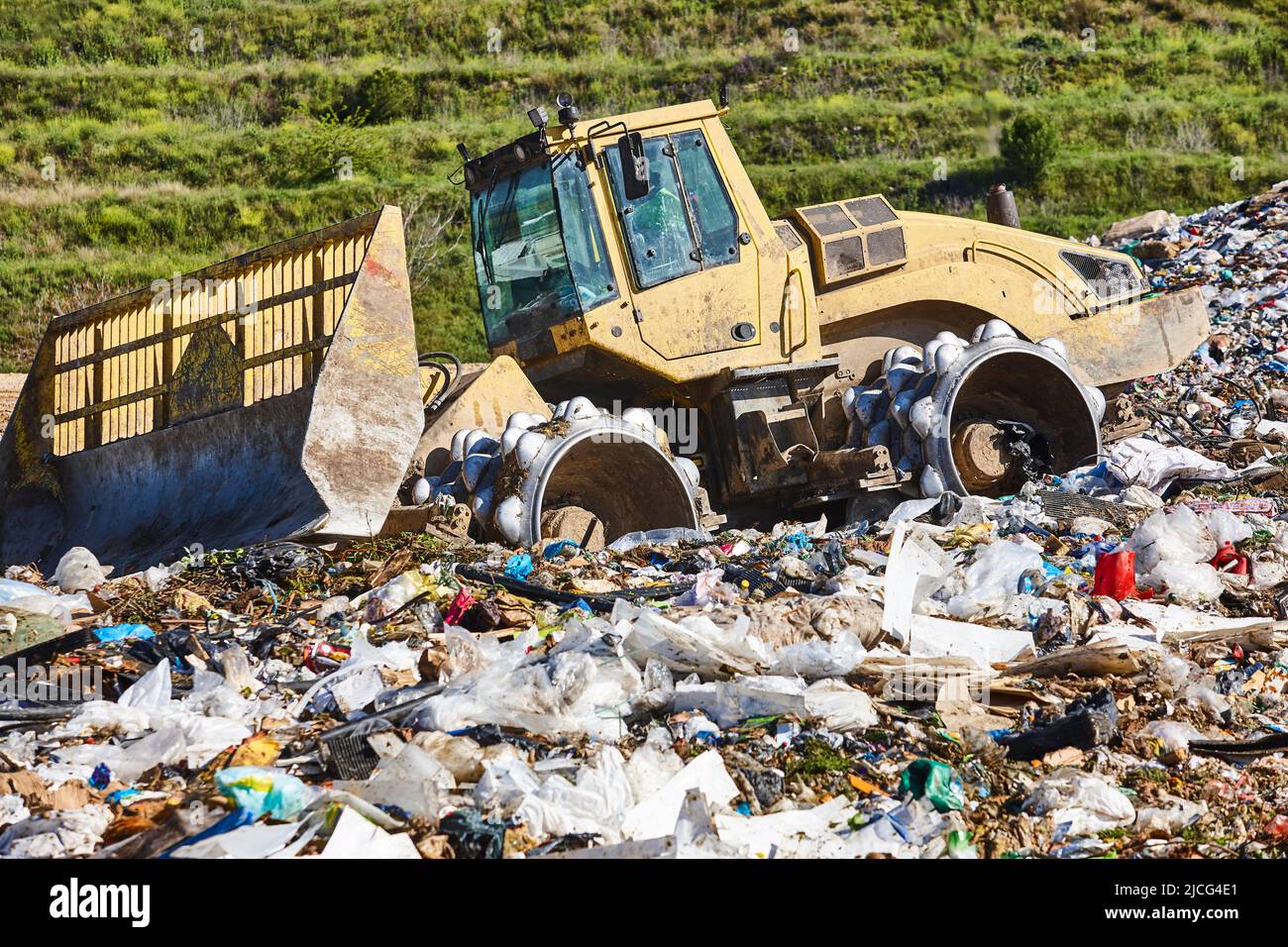 Heavy machinery shredding garbage in an open air landfill. Pollution ...
