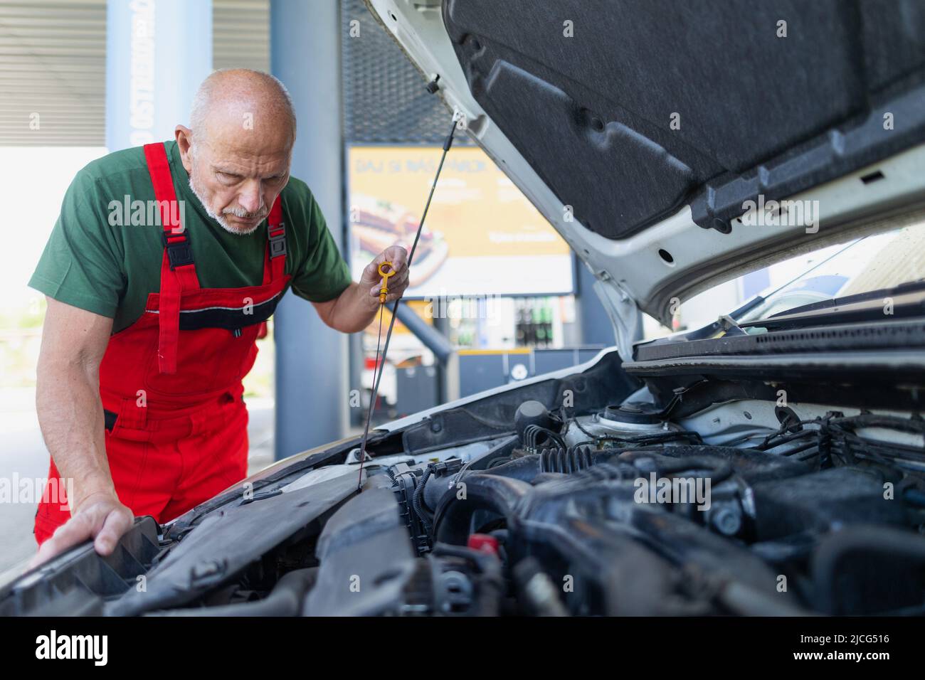 Senior mechanic checking the oil level in the car engine Stock Photo ...