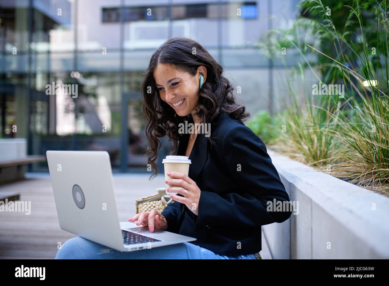 Successful happy businesswoman sitting and using laptop outside the ...