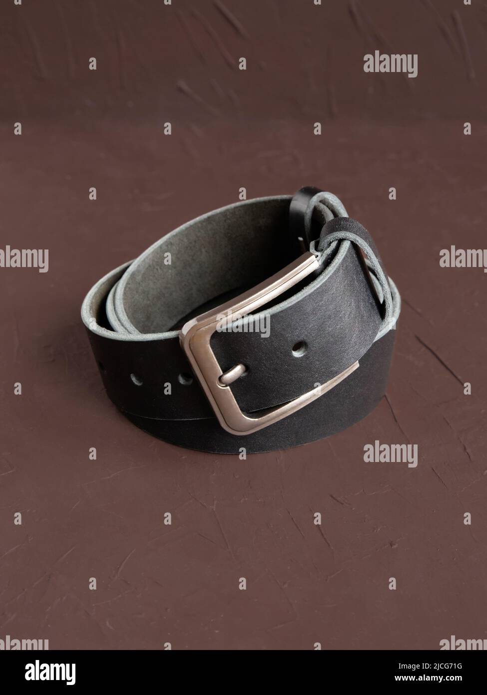 Rolled-up black fashionable men's leather belt with metal buckle on ...
