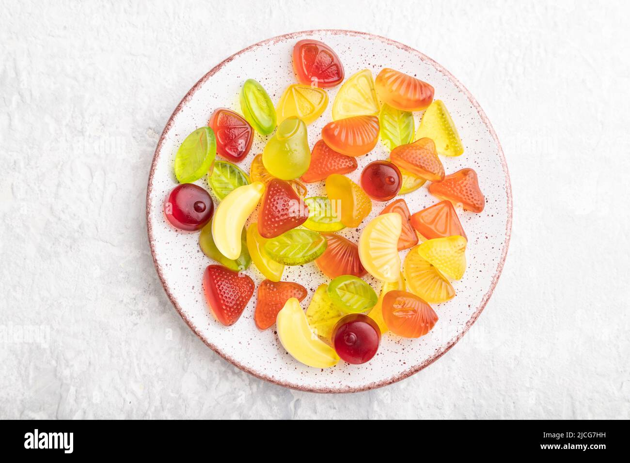 Various fruit jelly candies on plate on gray concrete background. top ...