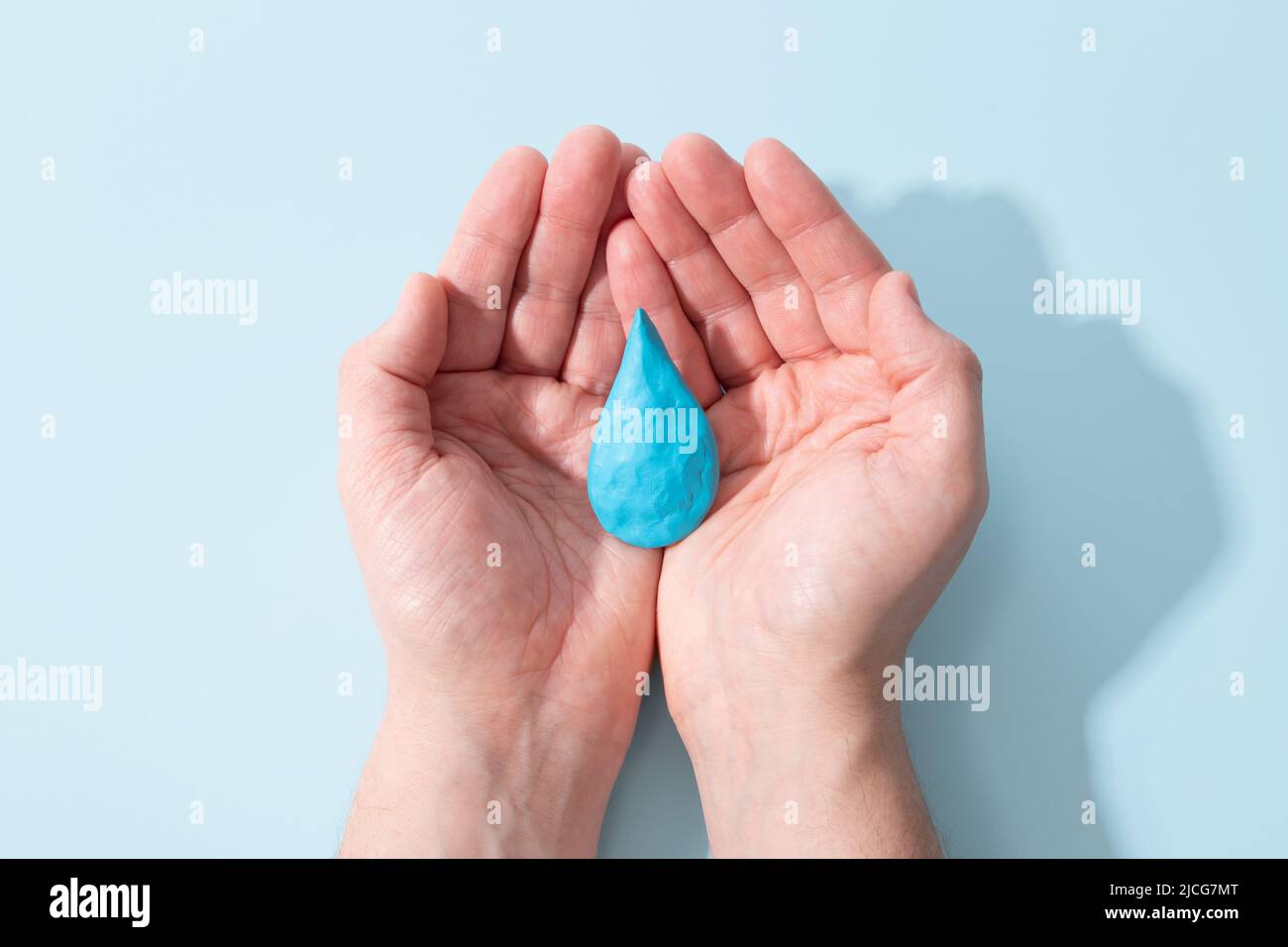 Holding water drop of blue plasticine modeling clay Mans hands. World ...