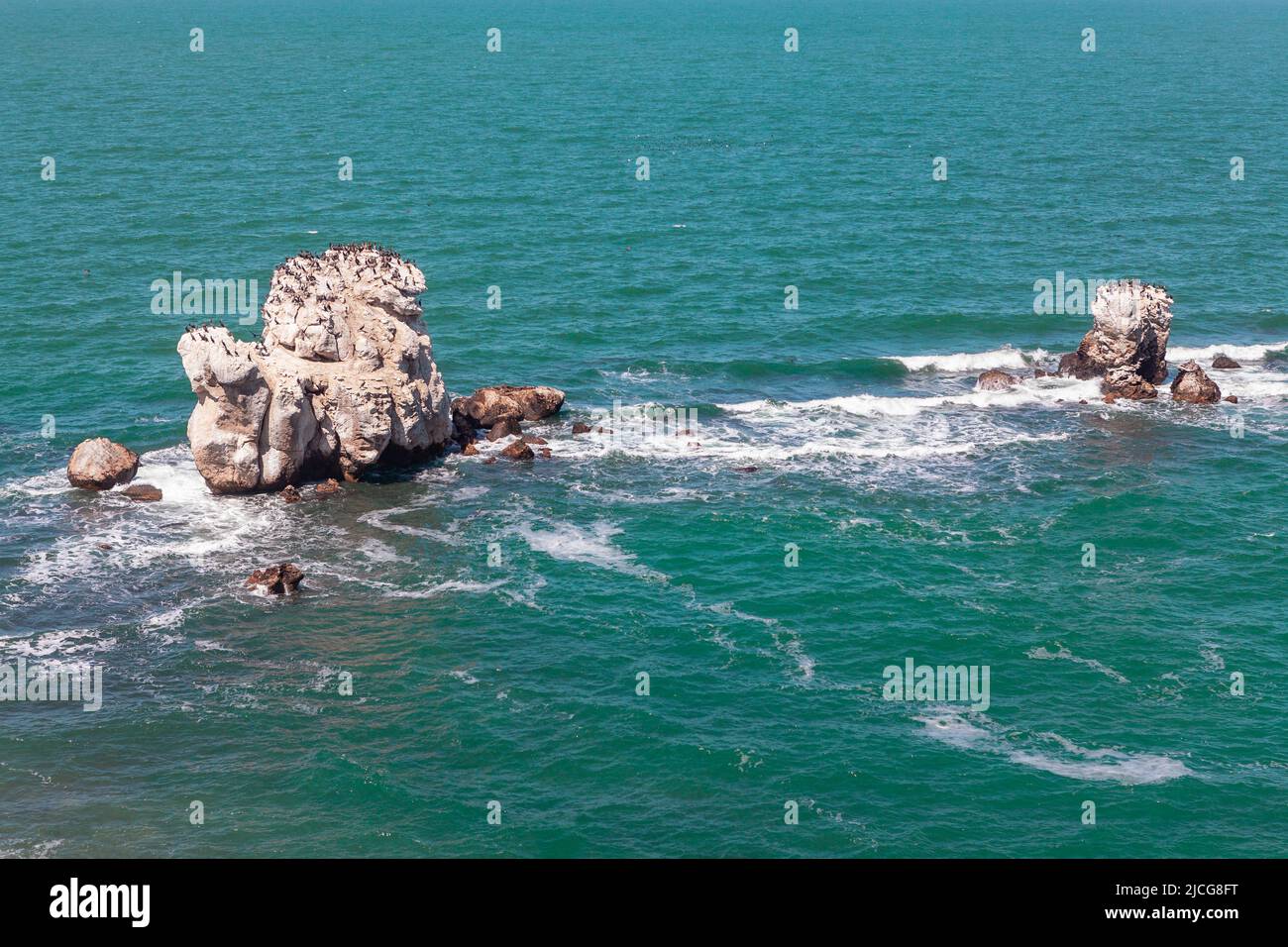 Rocks in the sea water . Flock of birds standing on the rocky isle ...