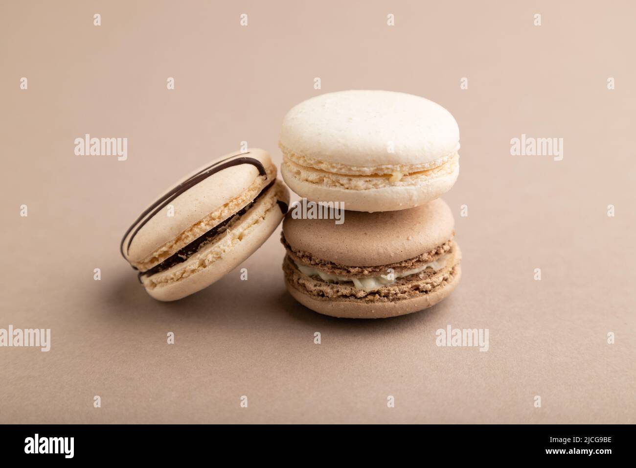 Brown and white macaroons on beige pastel background. side view, close ...