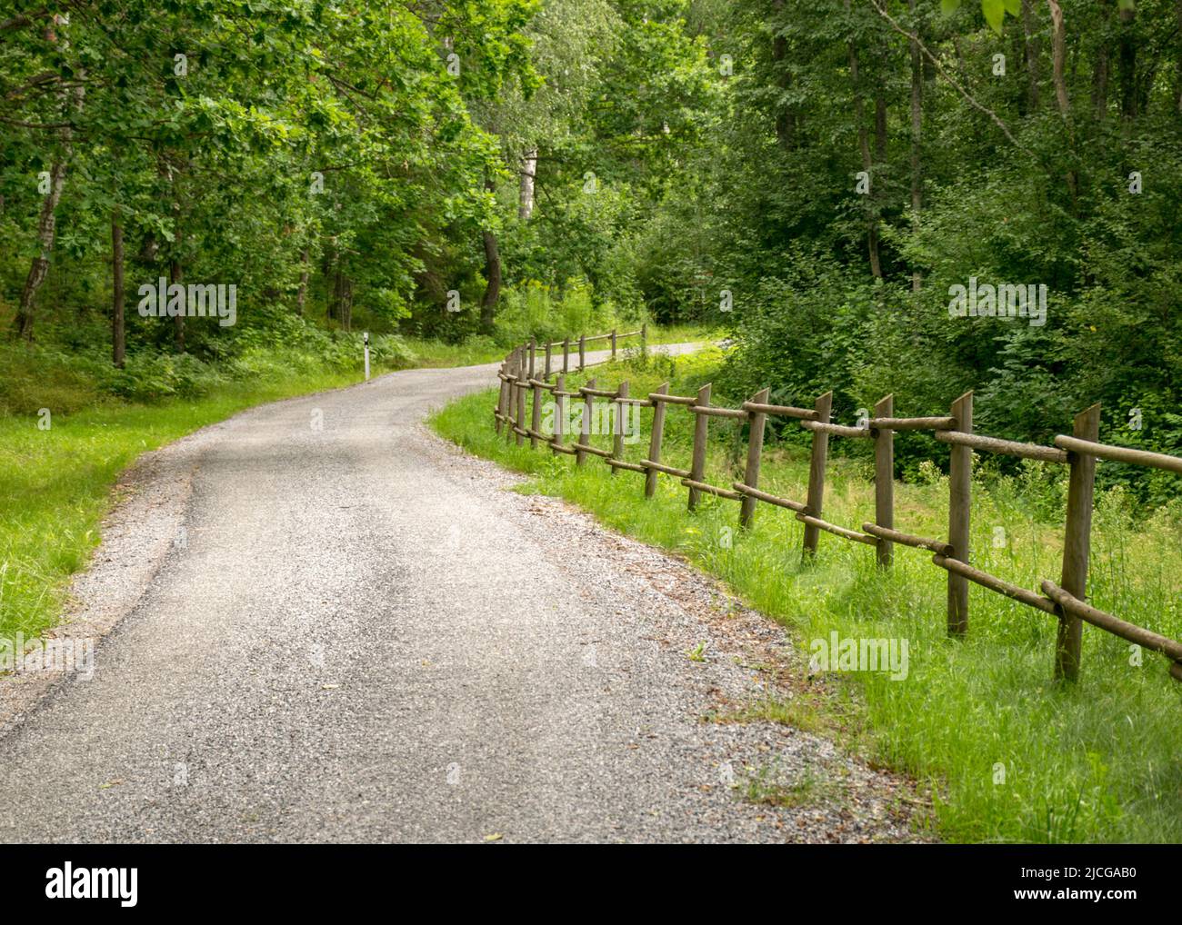 landscape with a simple country road and a wooden fence along the edge ...