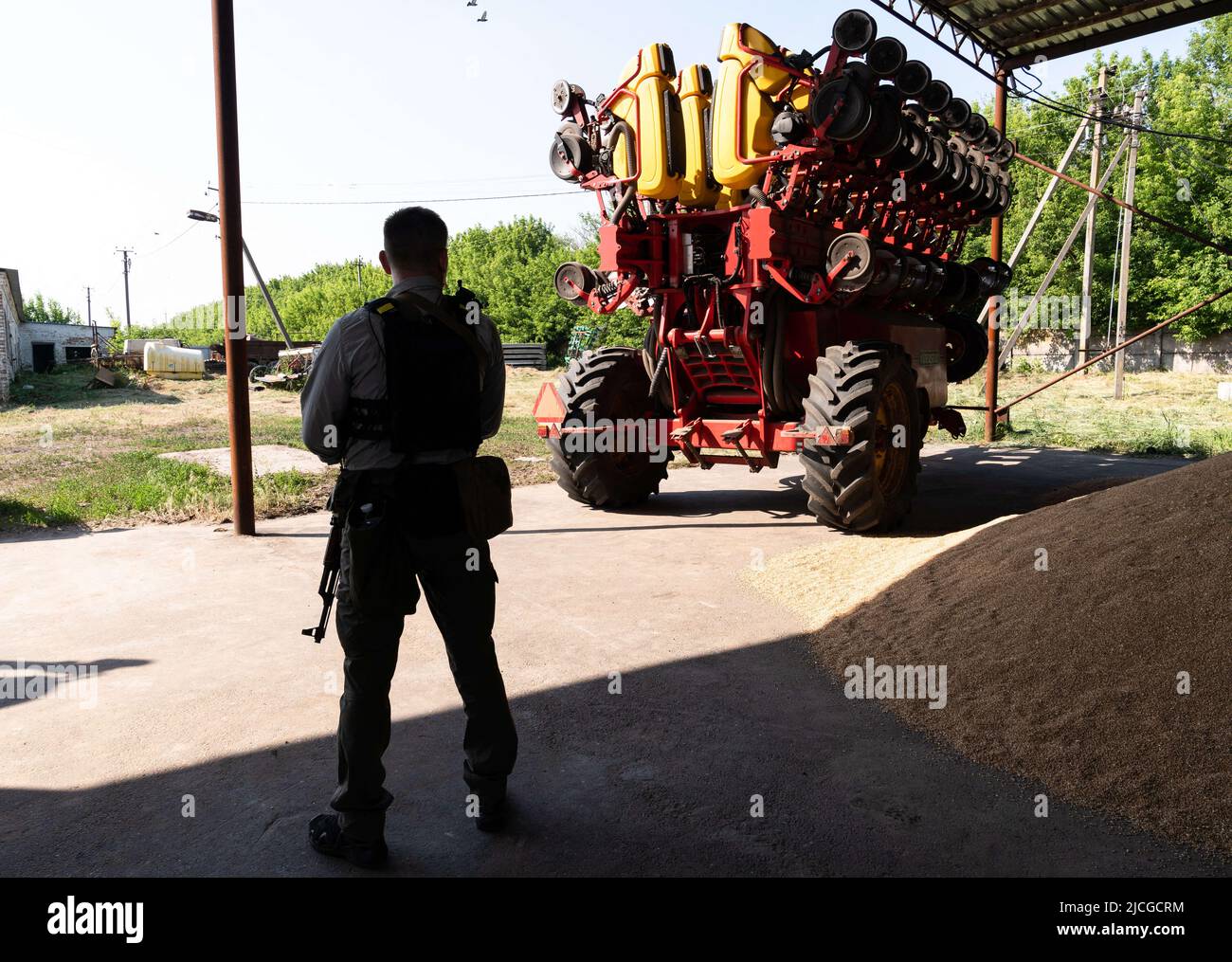 An armed guard stands next to an agricultural machine at a maize ...