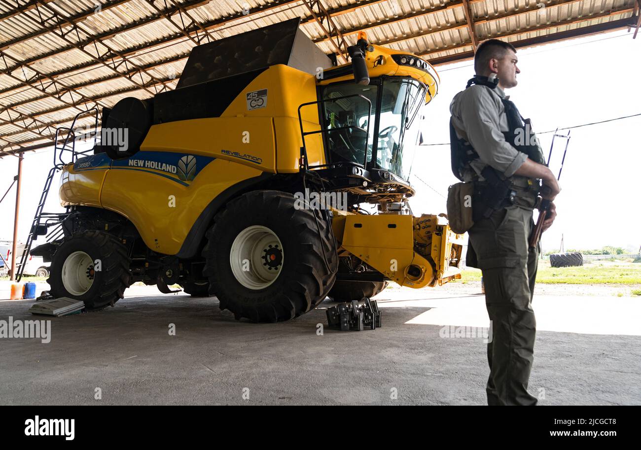 An armed guard stands next to an agricultural machine at a maize ...