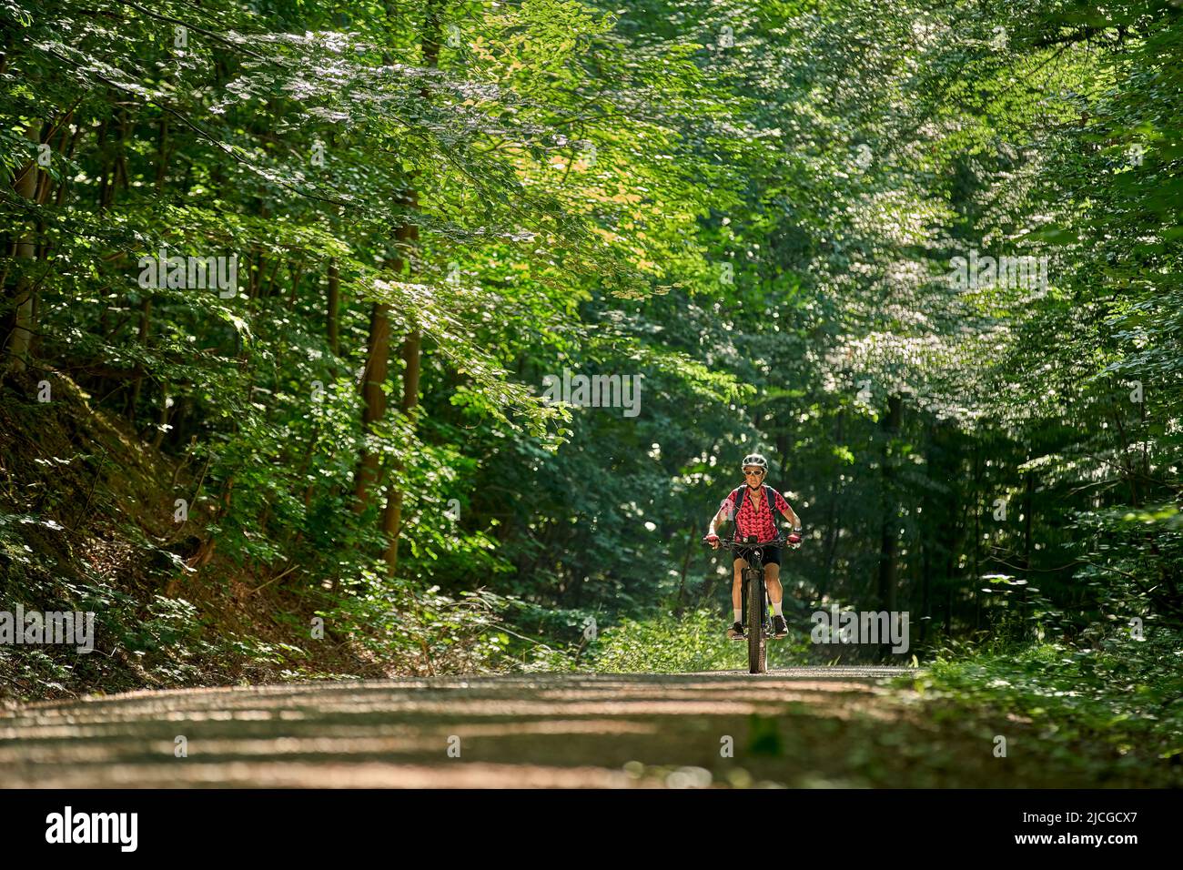 nice active senior woman riding her electric mountain bike in the green ...