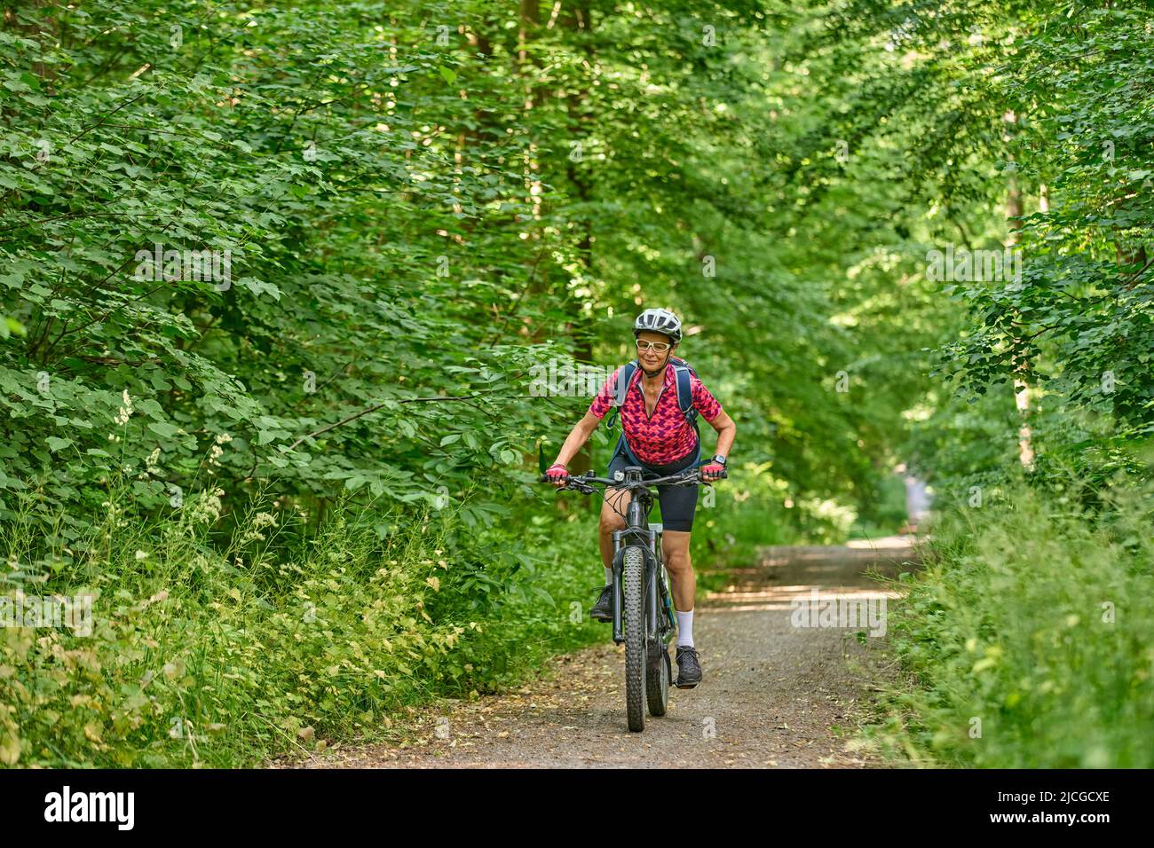nice active senior woman riding her electric mountain bike in the green ...