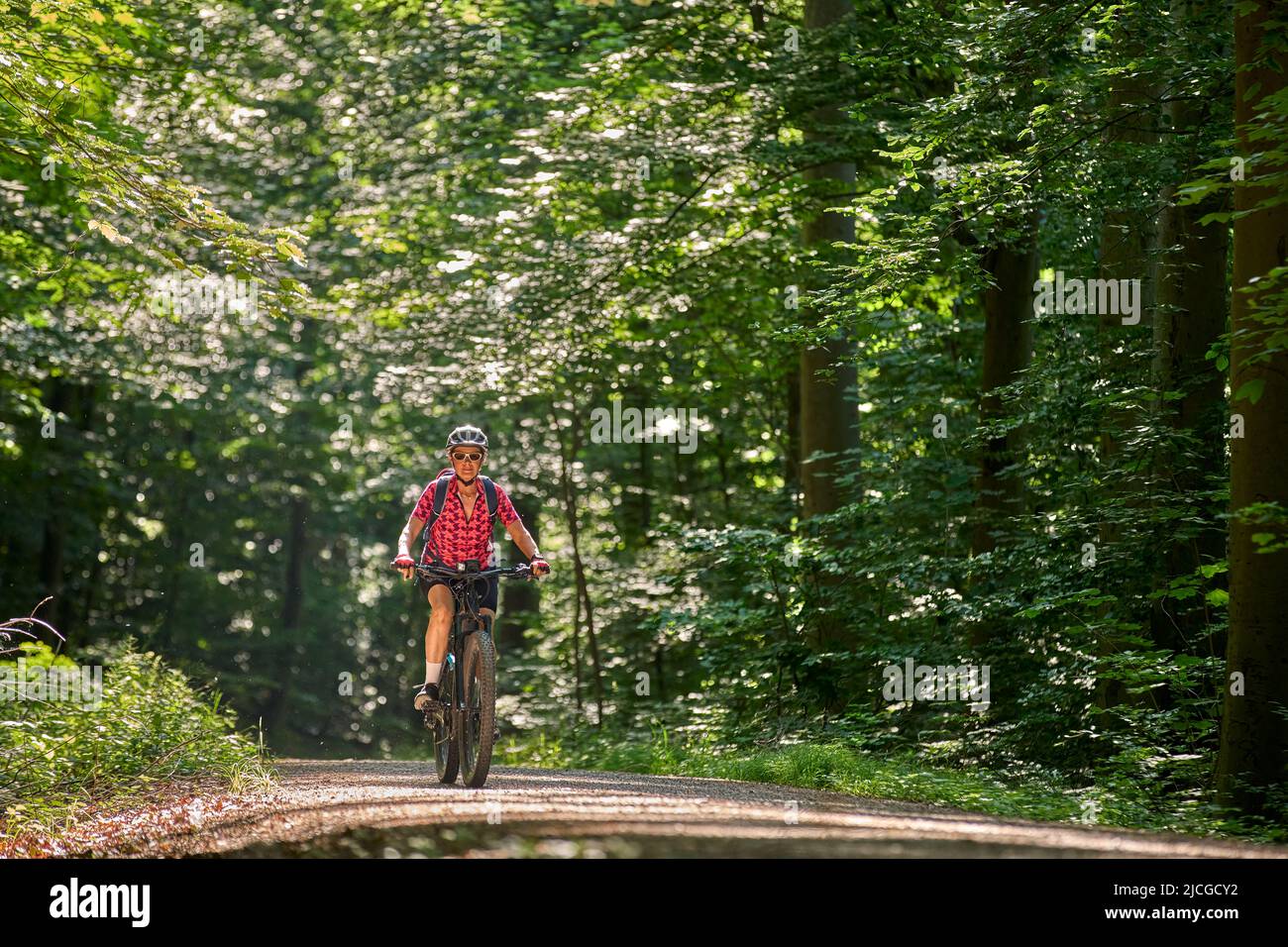nice active senior woman riding her electric mountain bike in the green ...