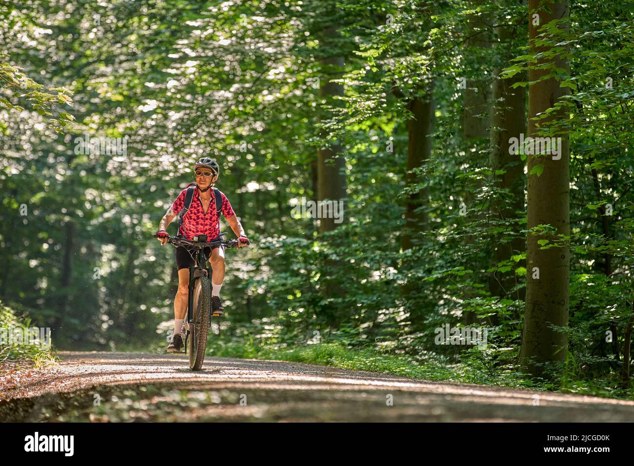 nice active senior woman riding her electric mountain bike in the green ...