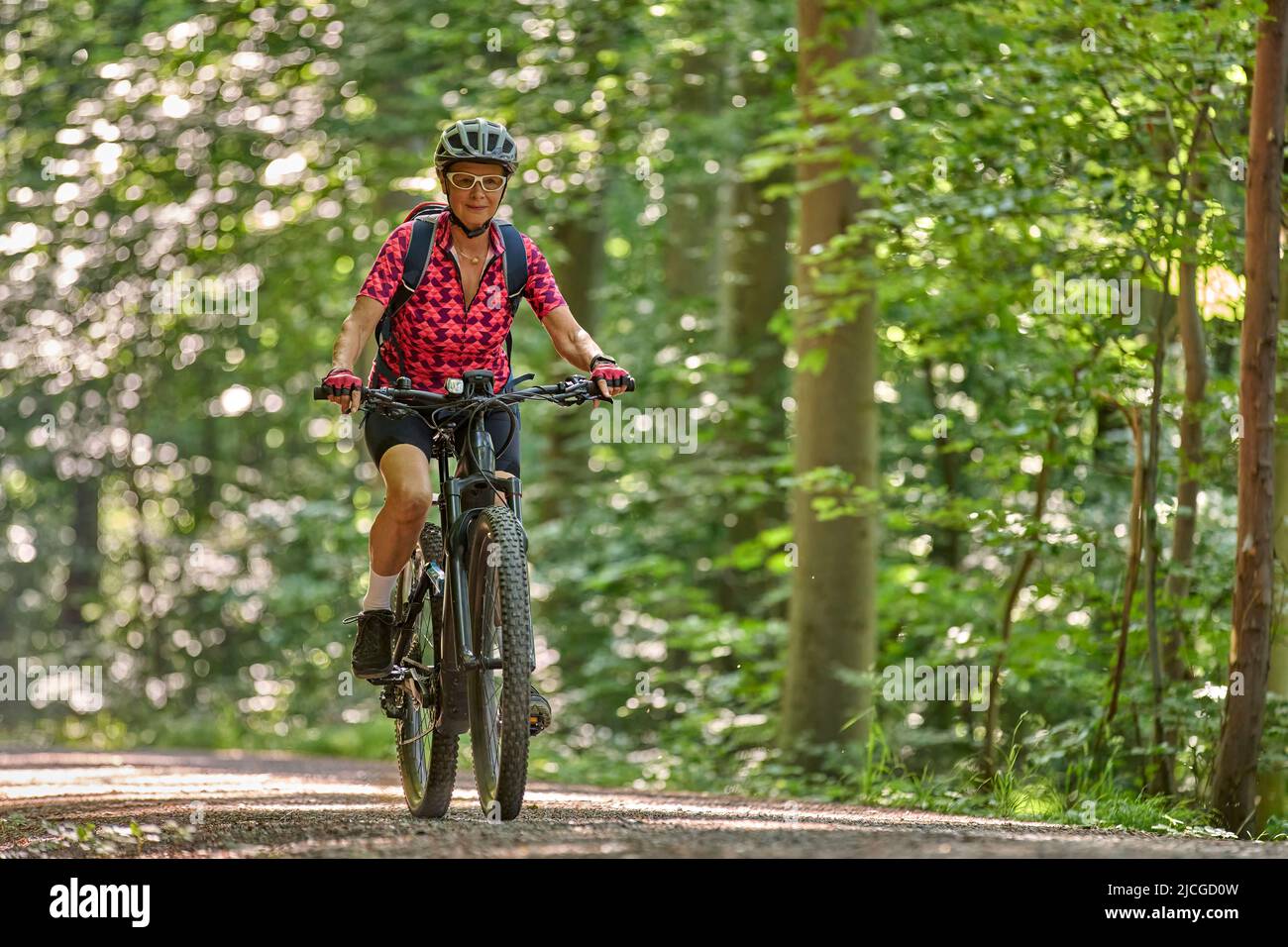 nice active senior woman riding her electric mountain bike in the green ...