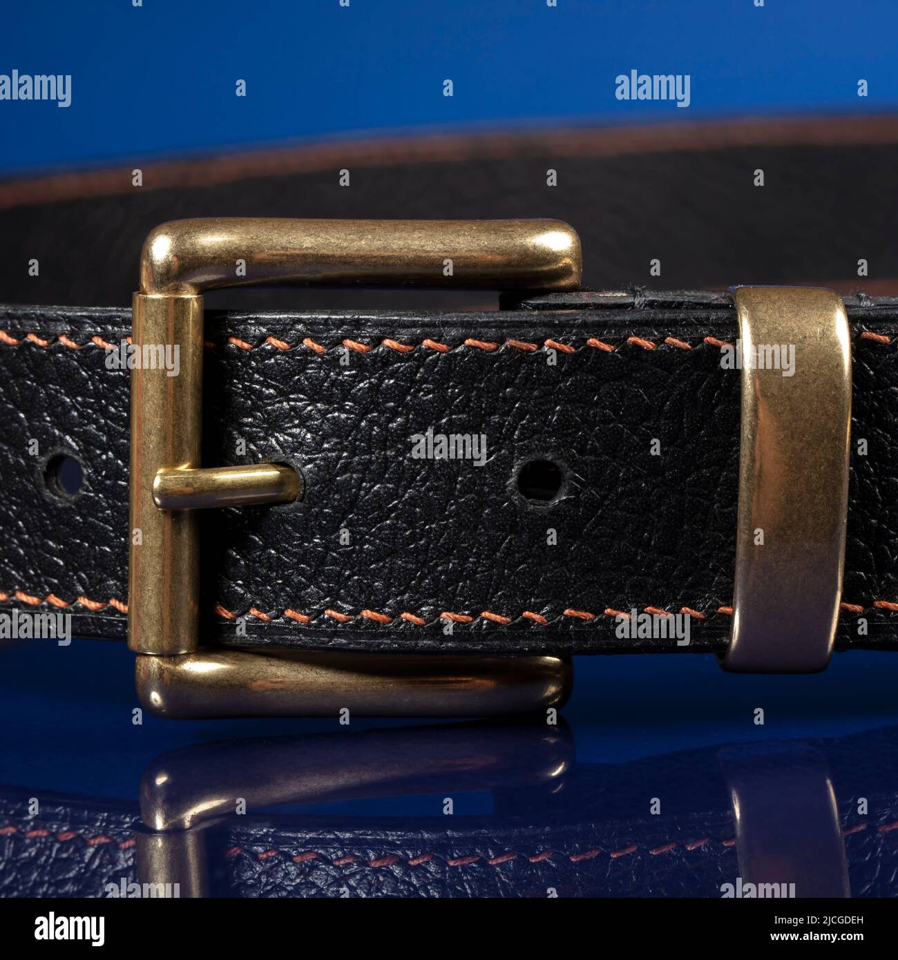 Black leather belt on a dark blue background Stock Photo - Alamy