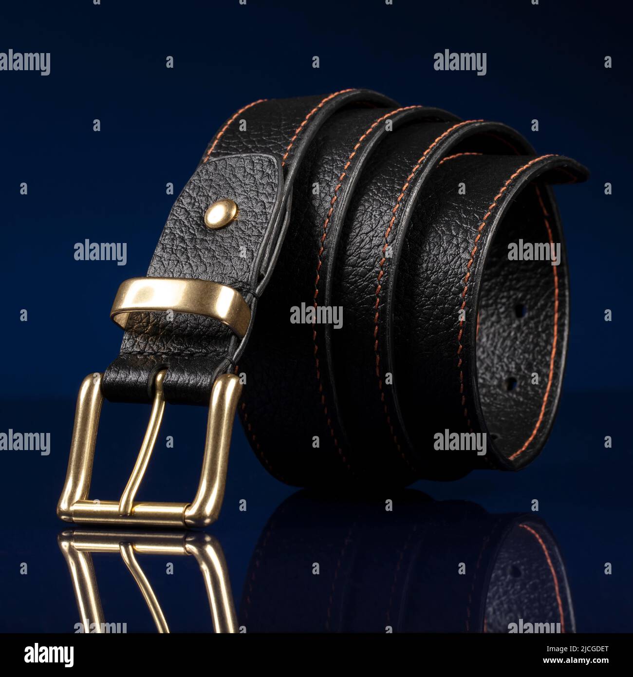 Black leather belt on a dark blue background Stock Photo - Alamy