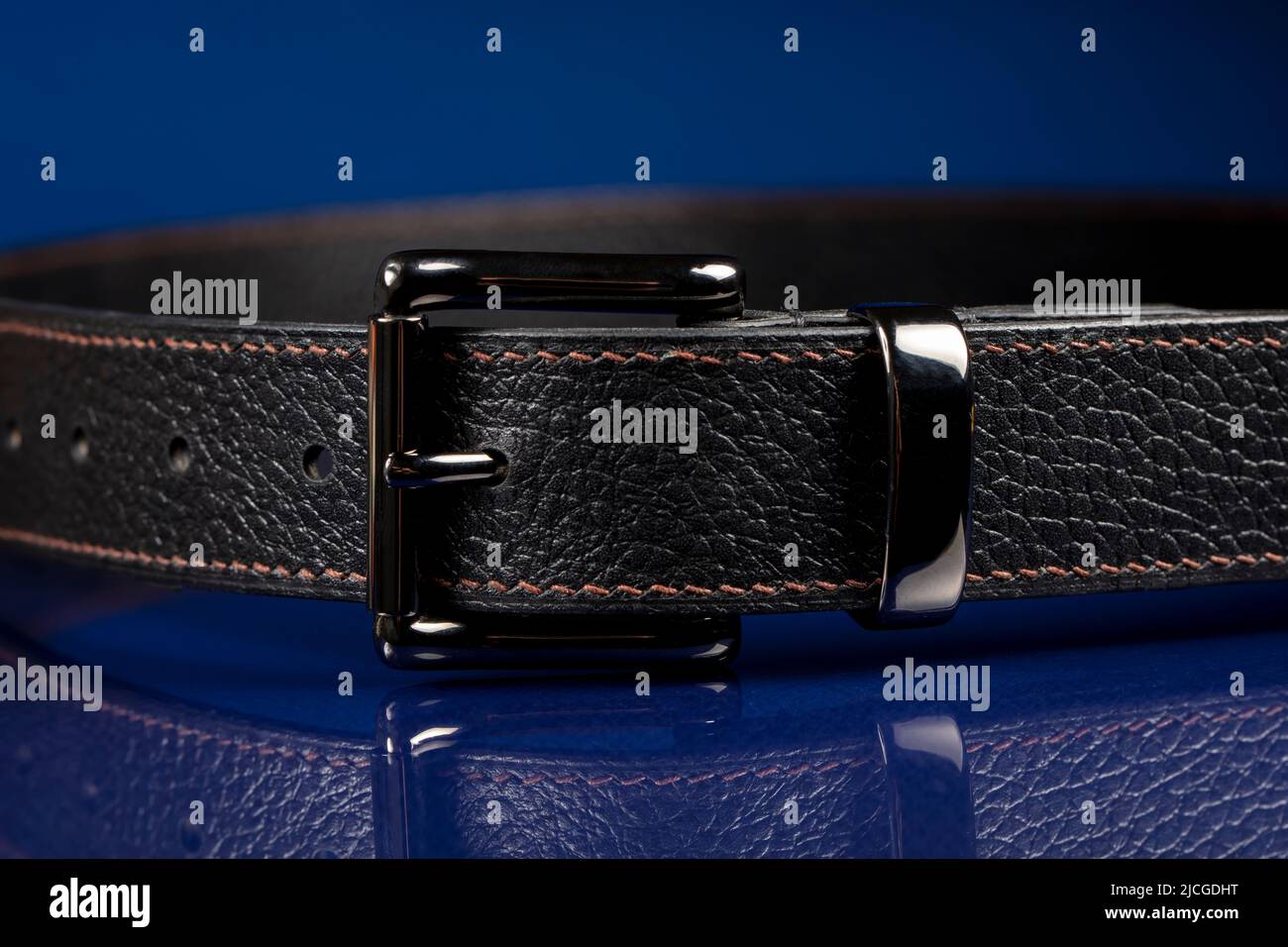 Black leather belt on a dark blue background Stock Photo - Alamy