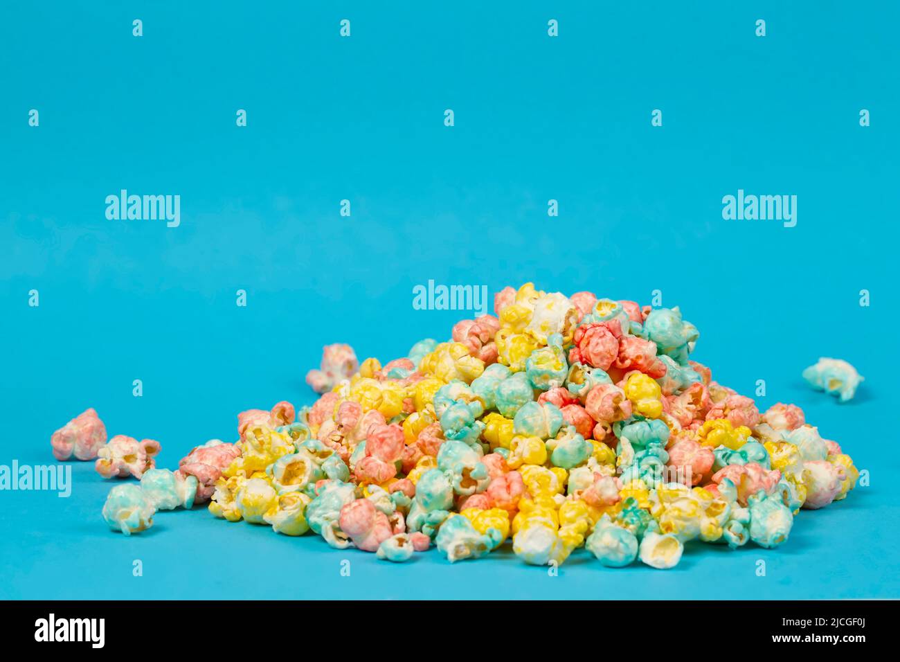Multi-colored popcorn is scattered on a blue background. Colorful ...