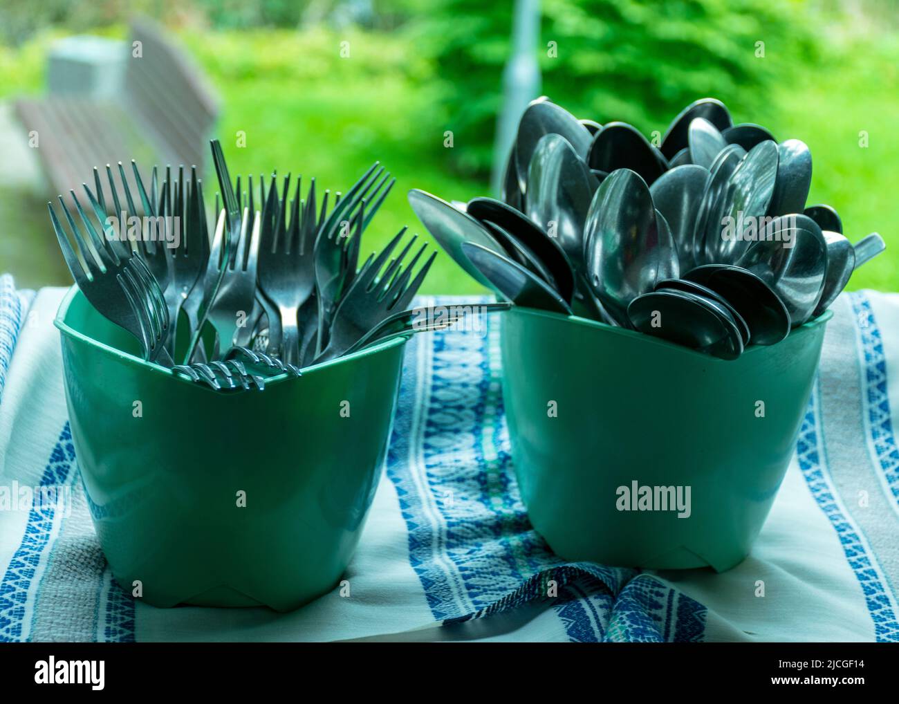 school kitchen canteen, metal spoons and knives in green plastic ...