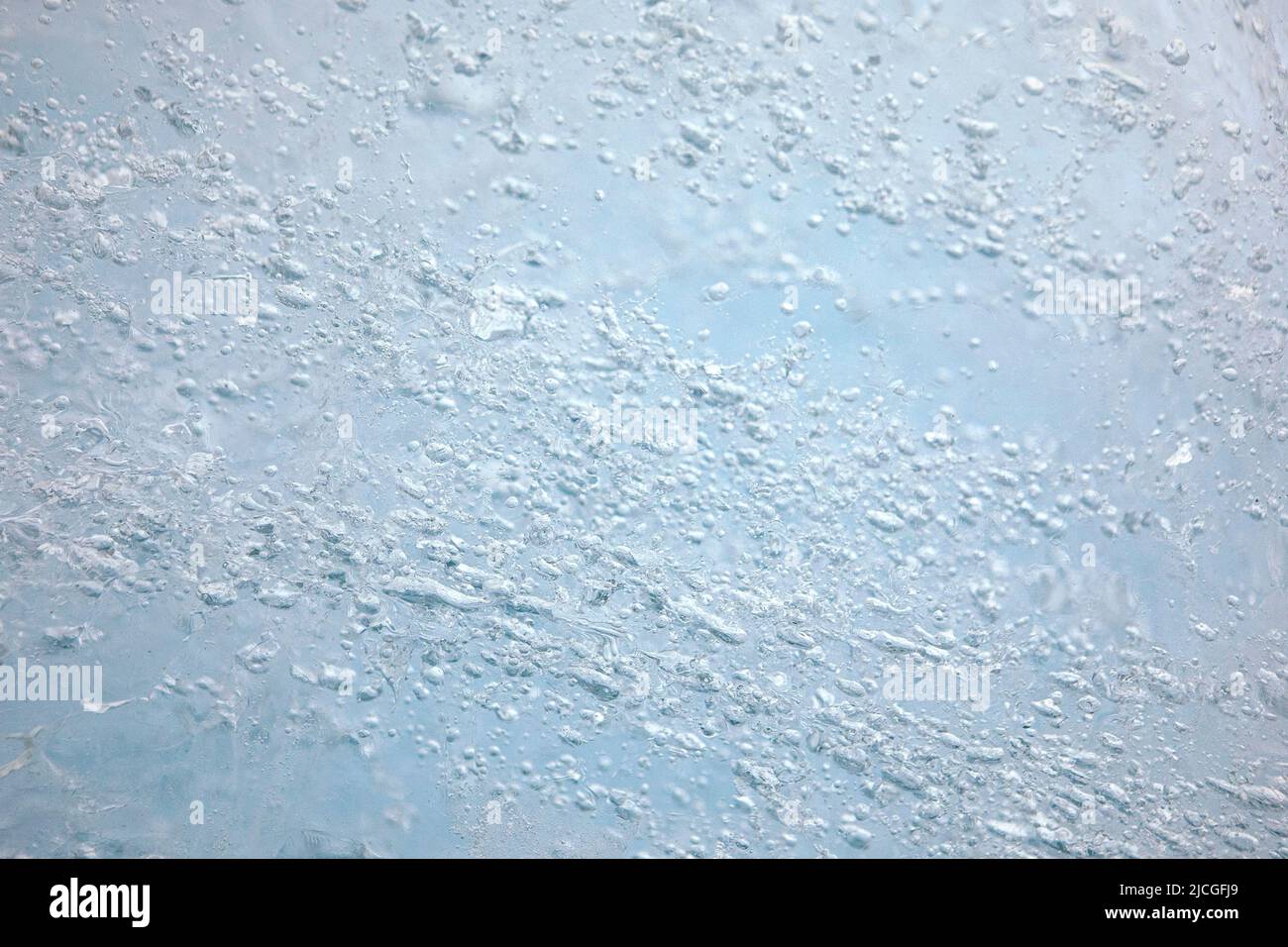 Blue ice surface, frozen plain background, air bubbles visible in ice ...