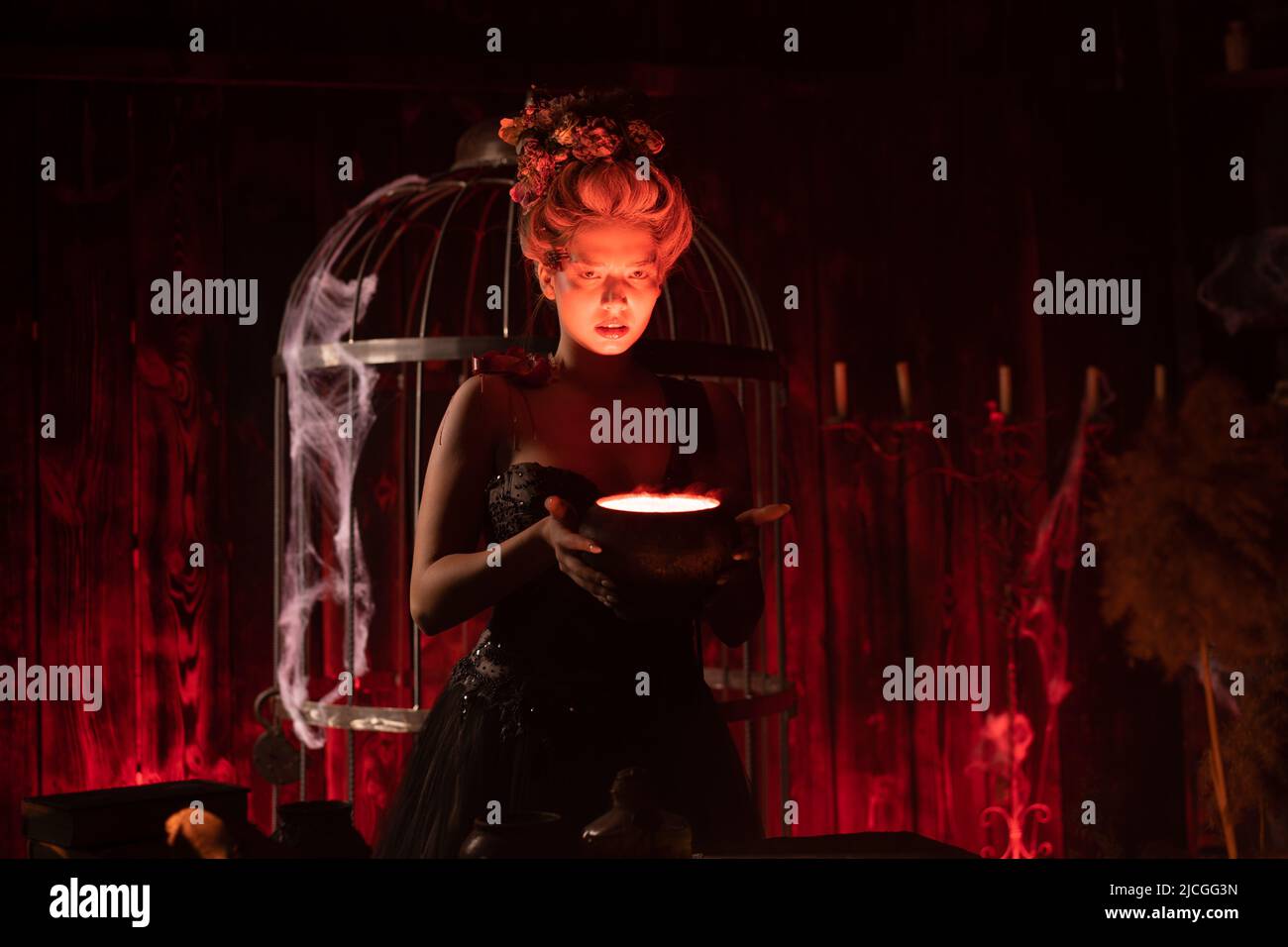 Halloween witch with cauldron. Beautiful young woman conjuring, making ...