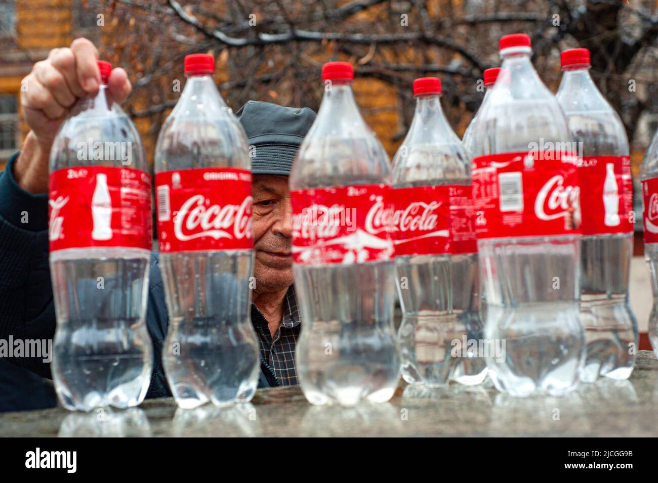 An old Bulgarian man filling Coca-Cola bottles with mineral water at a ...