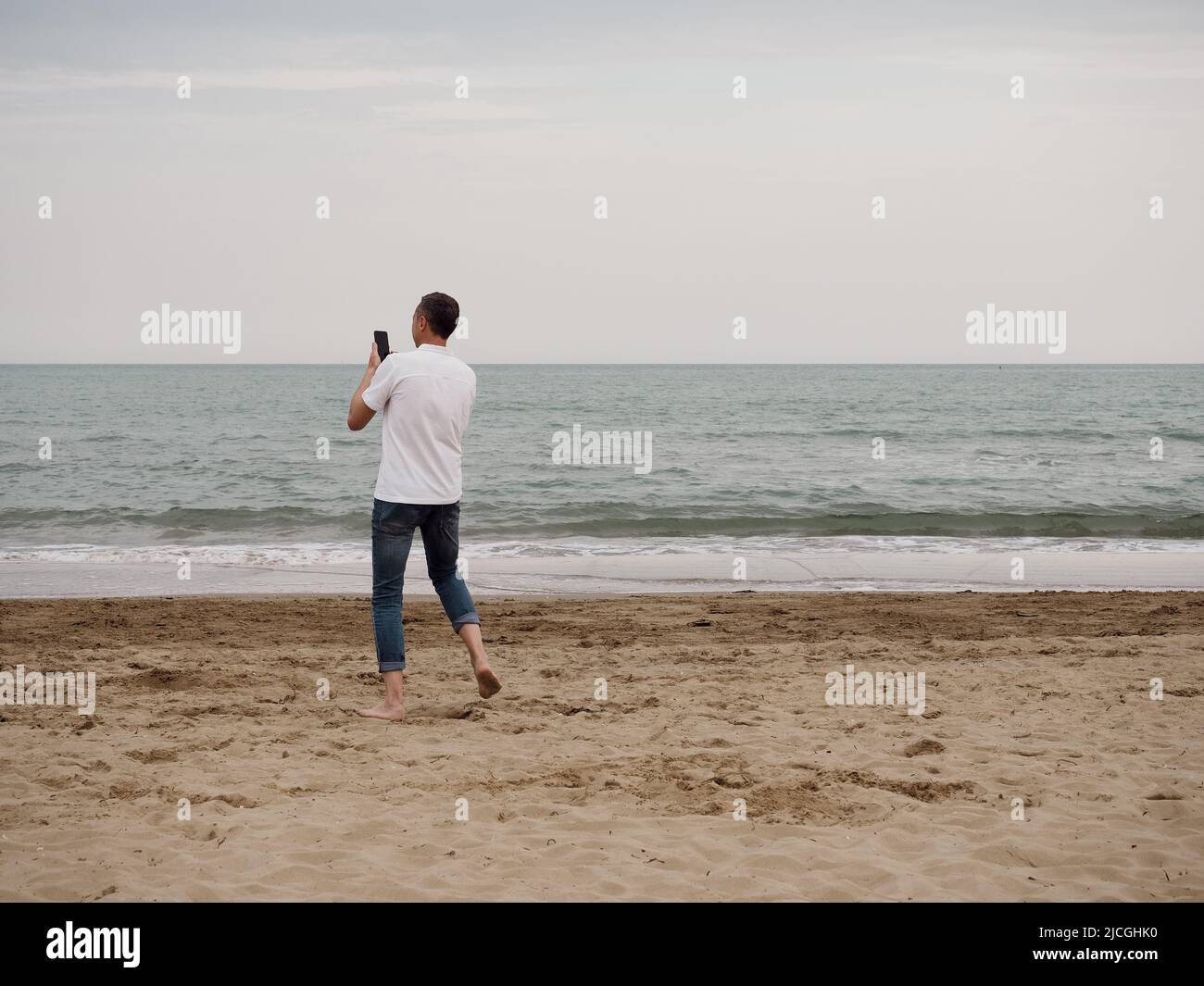 person alone at the sea shooting a photo with smartphone camera Stock ...