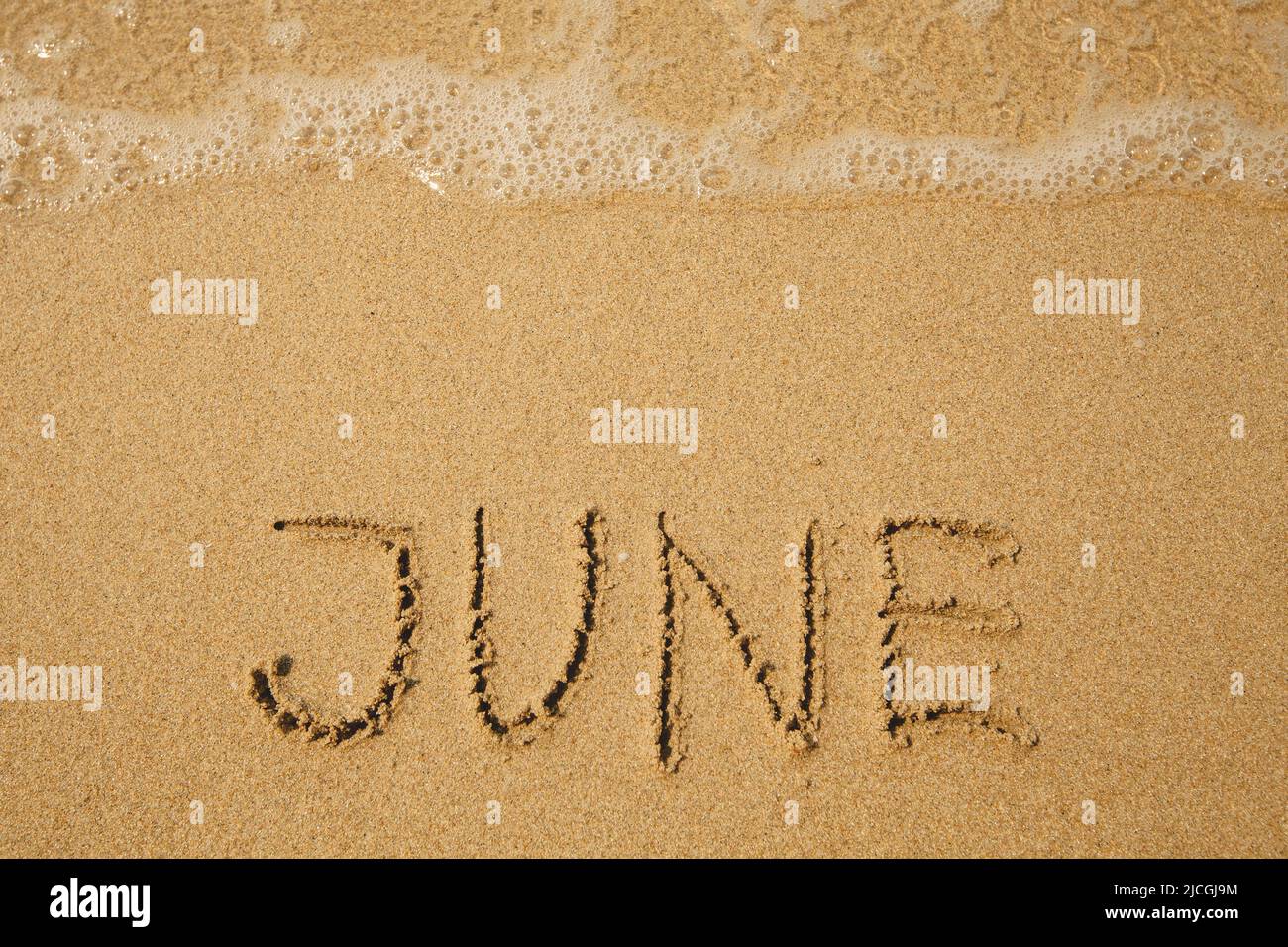 June - handwritten on the soft beach sand Stock Photo - Alamy
