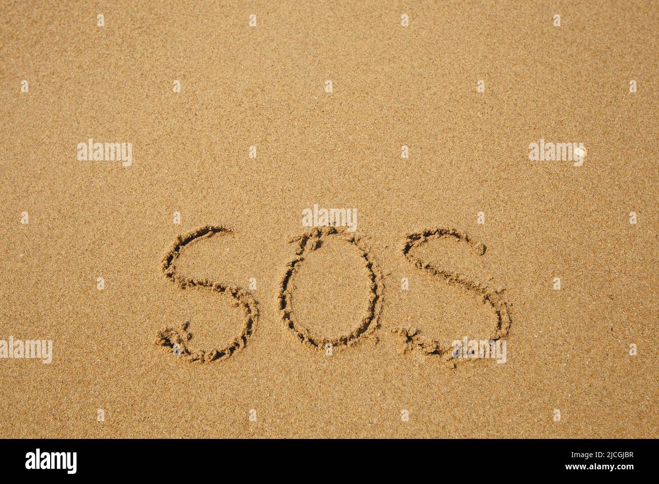 SOS - handwritten on the soft beach sand Stock Photo - Alamy