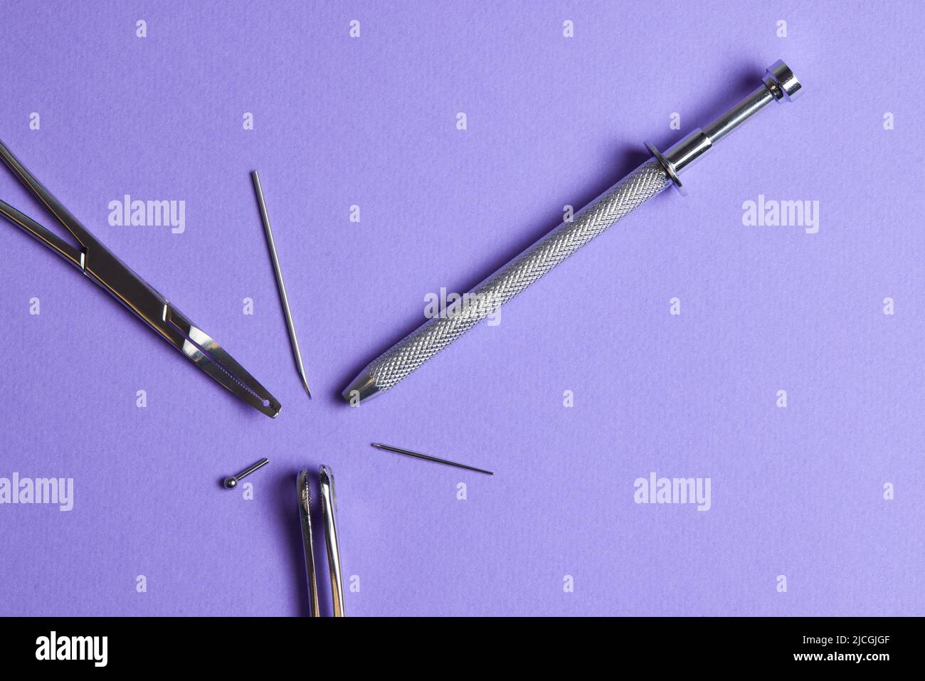 Piercing earrings close-up. On a Violet background Stock Photo - Alamy