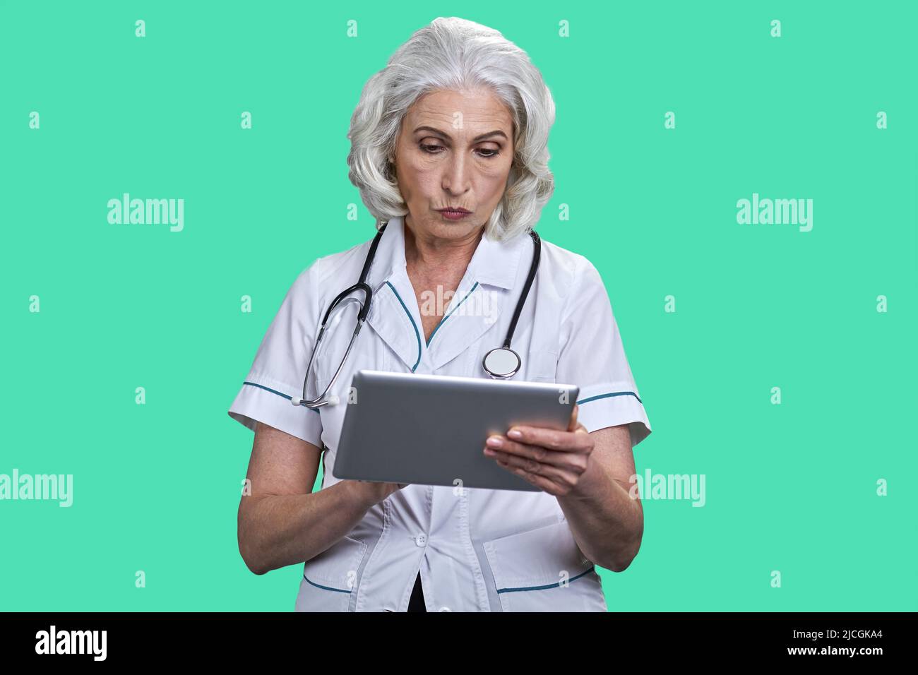 Concentrated female doctor with stethoscope looking at digital tablet ...