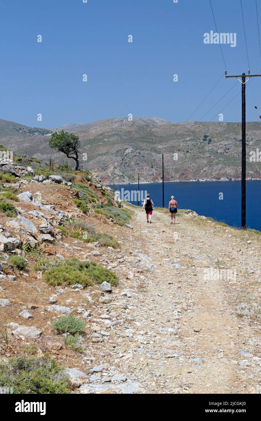 Two women walkers on a rugged and dusty path on Tilos island, near ...
