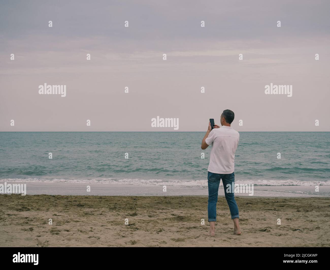 person alone at the sea shooting a photo with smartphone camera Stock ...
