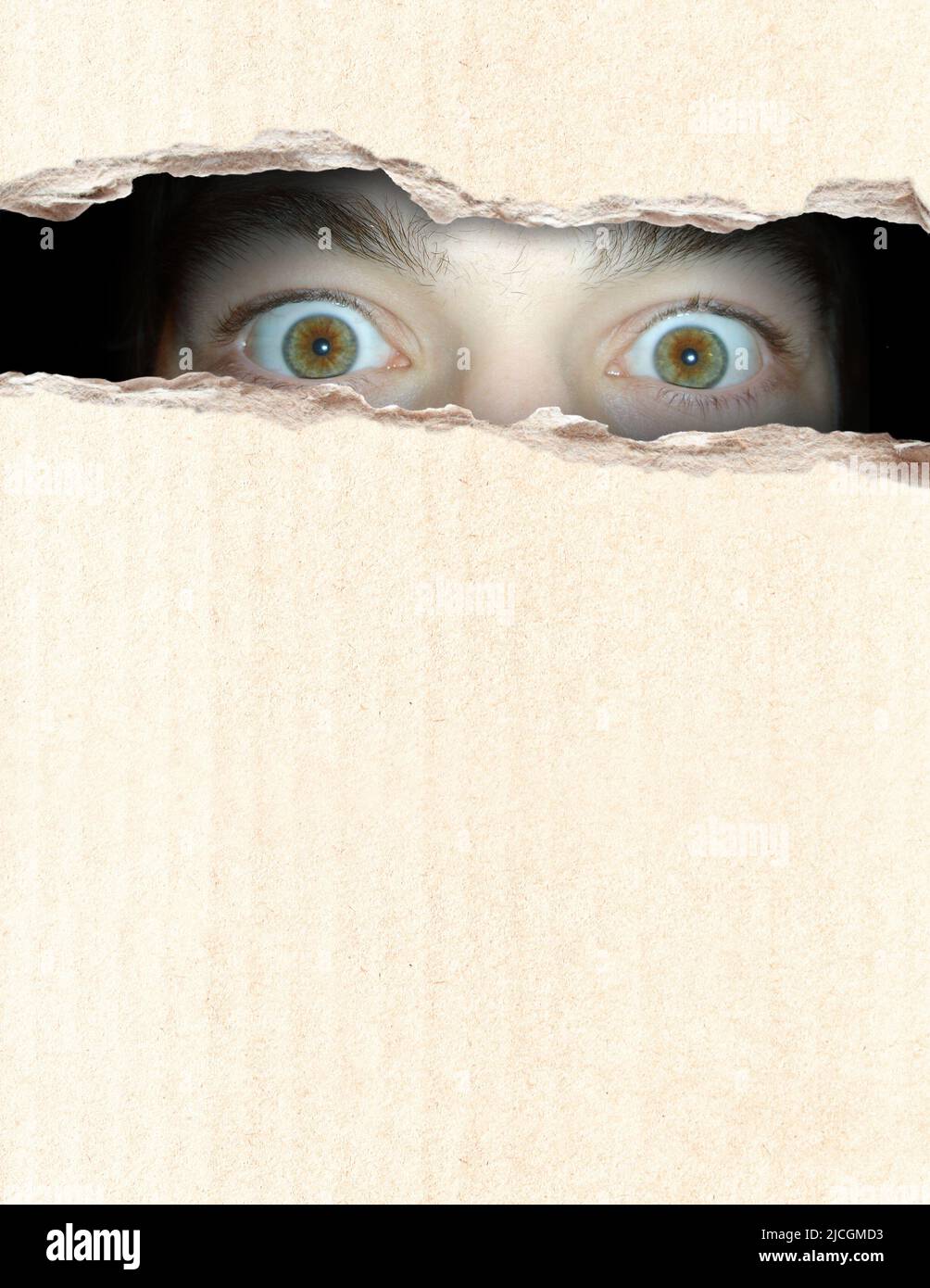 A look from darkness. Young caucasian man looking through ripped paper ...