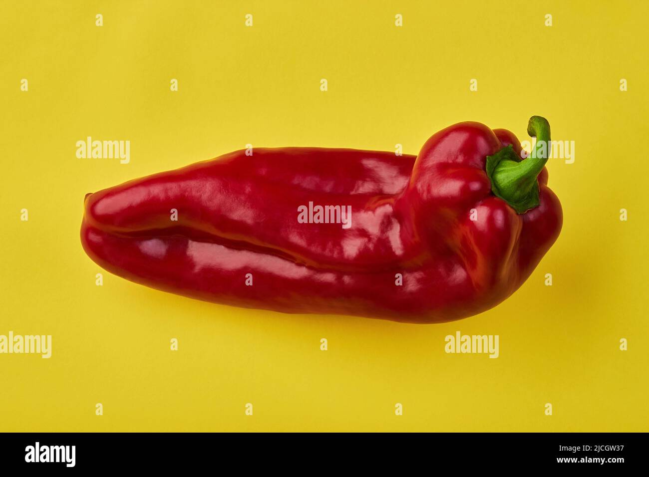 Red pepper of an unusual shape on a yellow background. Isolated object ...