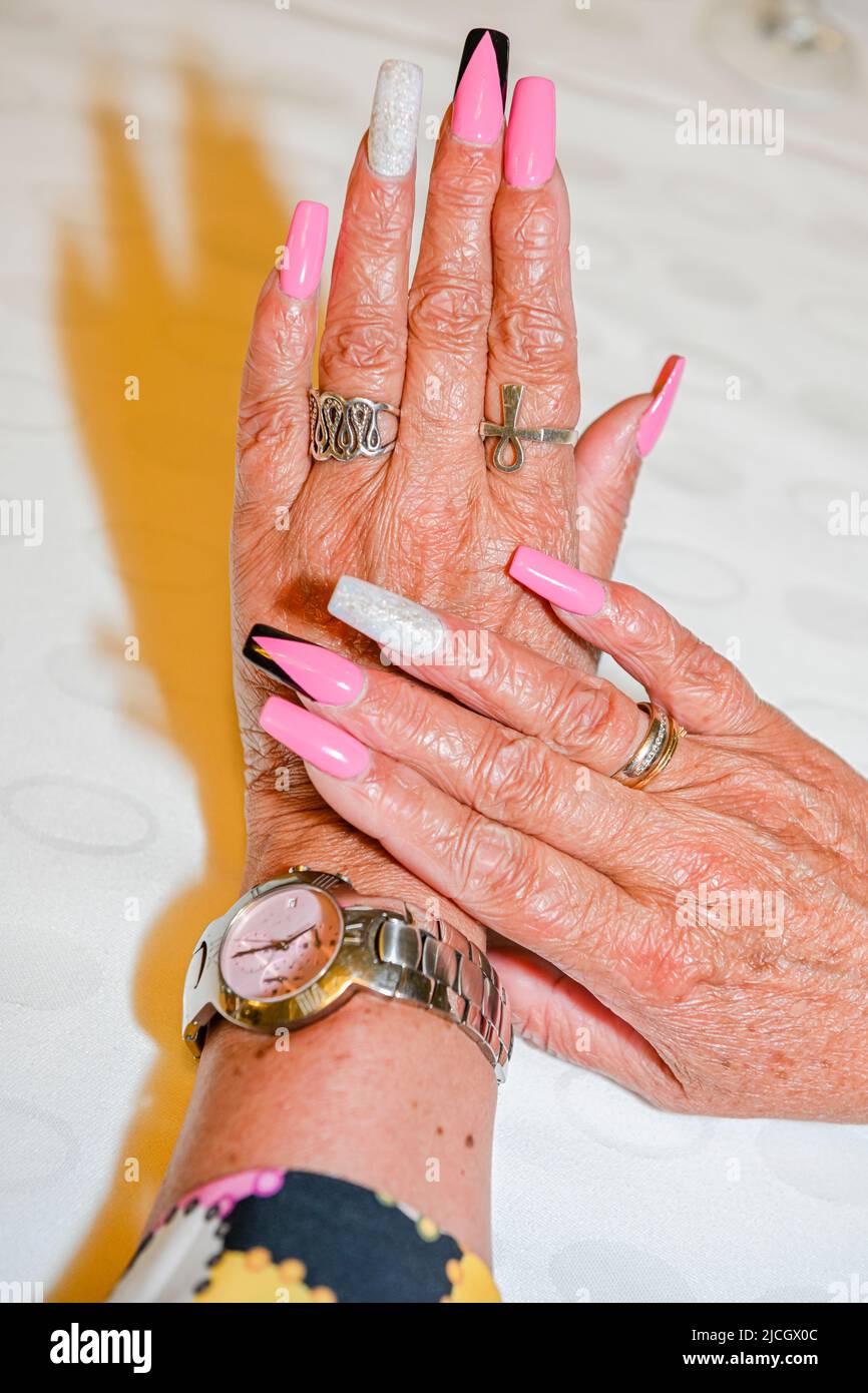 Female hands of an elderly person with nail manicure. Isolated on white ...
