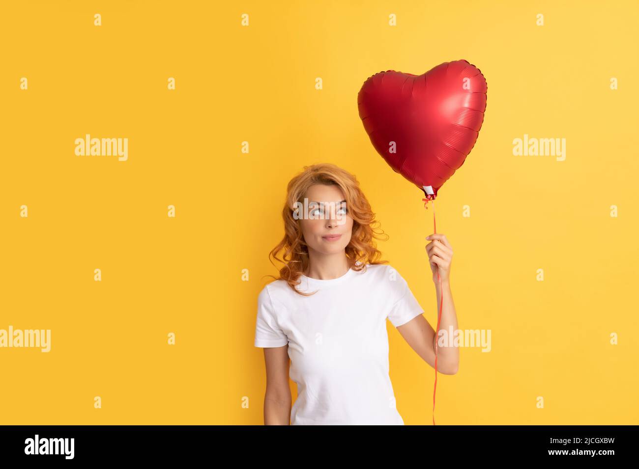 thoughtful redhead lady with romantic gift of party balloon. charity ...