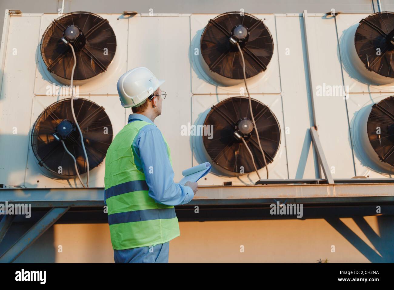 Service engineer in uniform inspecting industrial refrigeration system ...