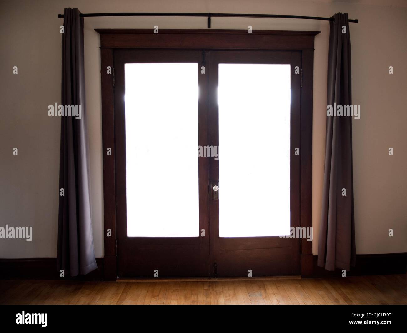 Entrance to home glass doors with drapes and bright light entering ...