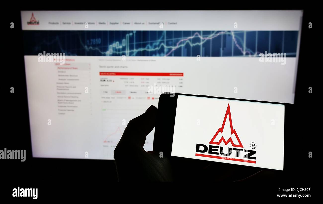 Person holding mobile phone with logo of German engine company Deutz AG ...