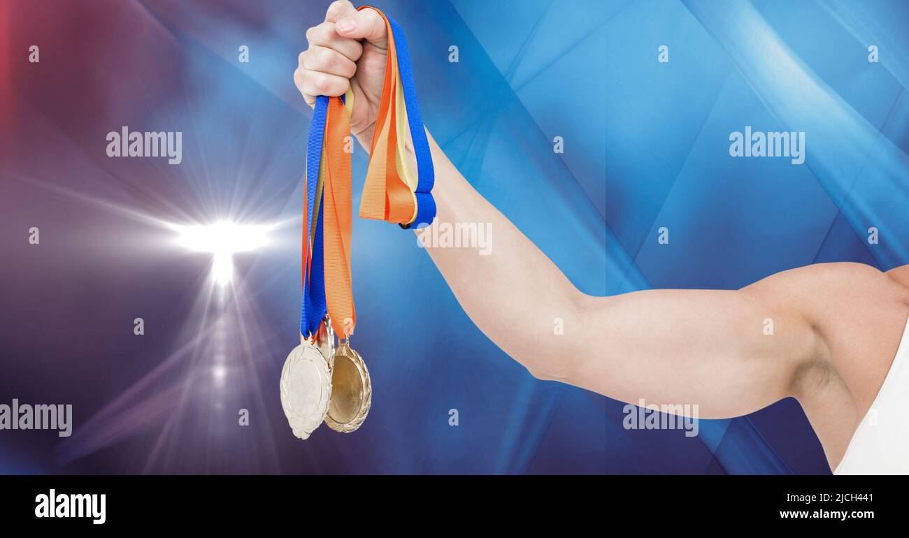 Hand holding multiple medals against spot of light on blue background ...