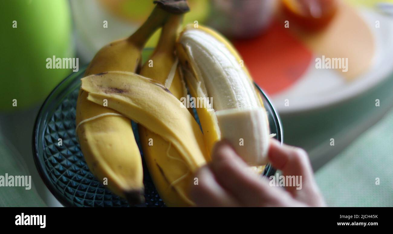 Close-up hand cutting piece of banana, person peeling fruit banana ...