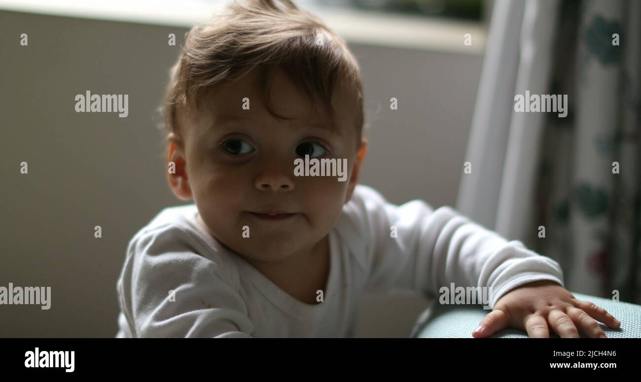 Cute baby learning to stand by supporting on furniture. Infant child ...