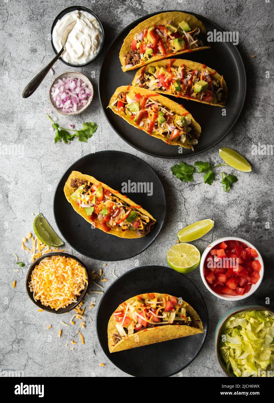Hard shell tacos on plates with beef, lettuce, tomatoes, cheese Stock ...